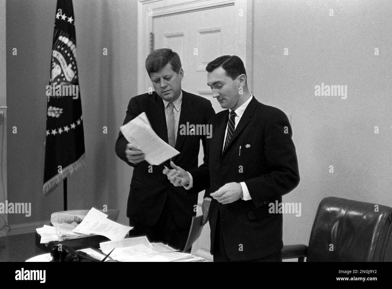 President John F. Kennedy studies official papers while his Appointmented Secretary Kenneth O ...