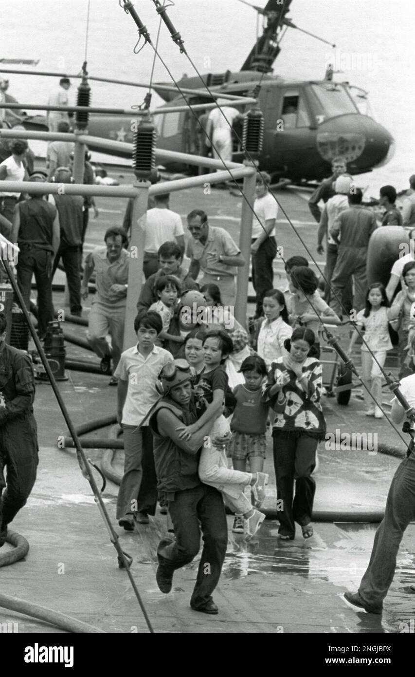 U.S. Marine helicopter crewmen carry Vietnamese civilians to safety ...