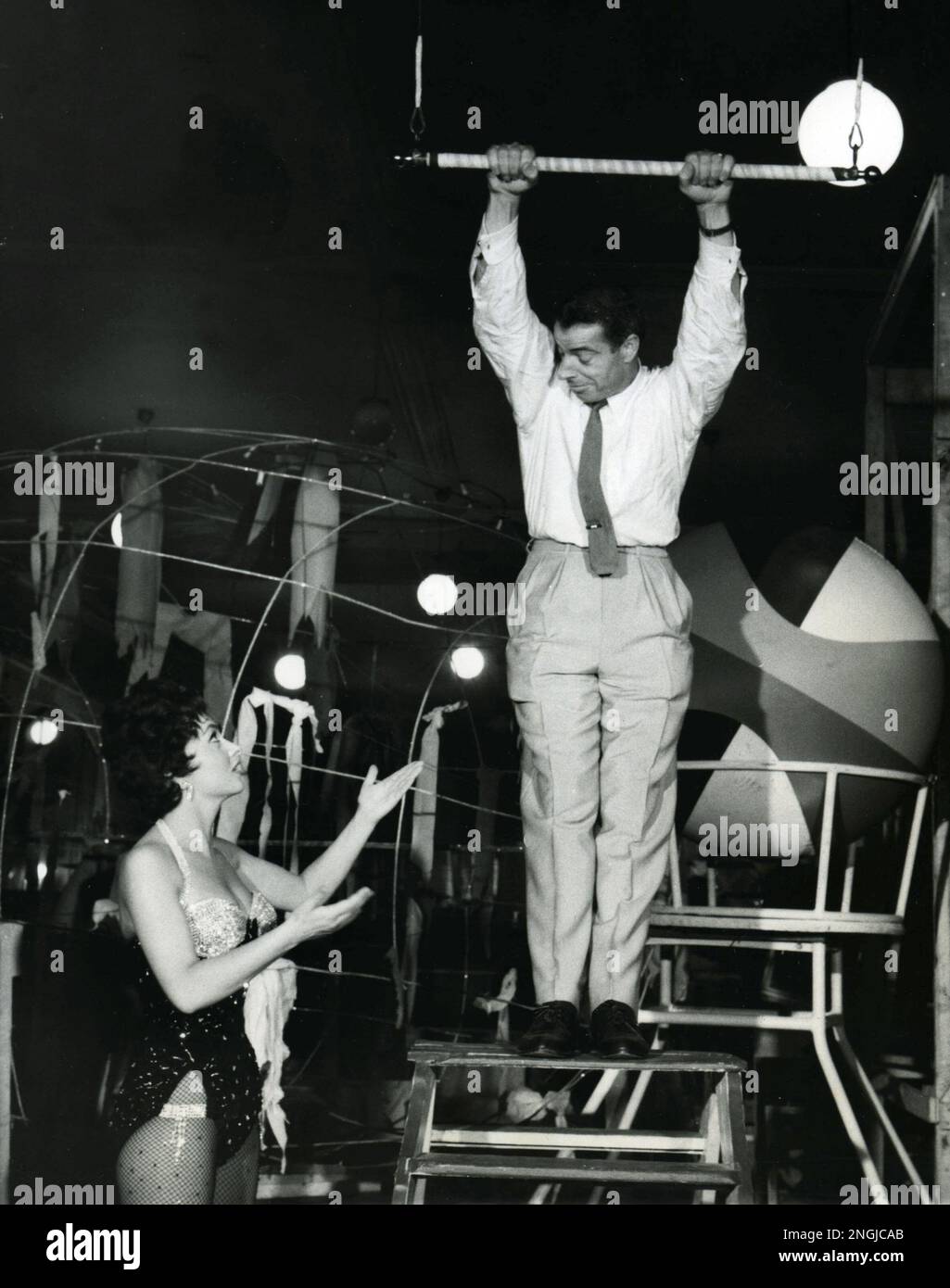 Baseball star Joe DiMaggio grasps a trapeze bar while visiting Italian ...
