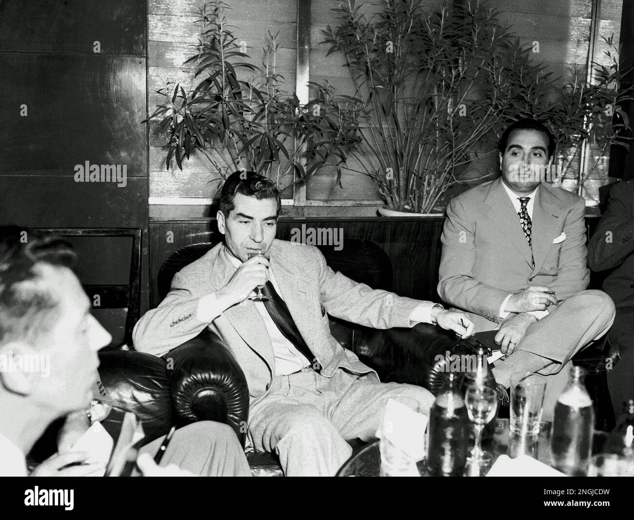 Reputed mobster Charles "Lucky" Luciano sips a drink during a news conference he called in the ...
