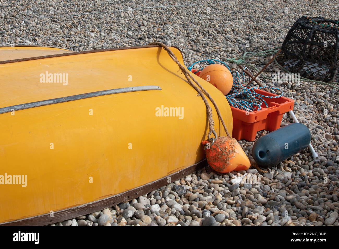 A small yellow fishing boat lies upturned on the beach in the village ...
