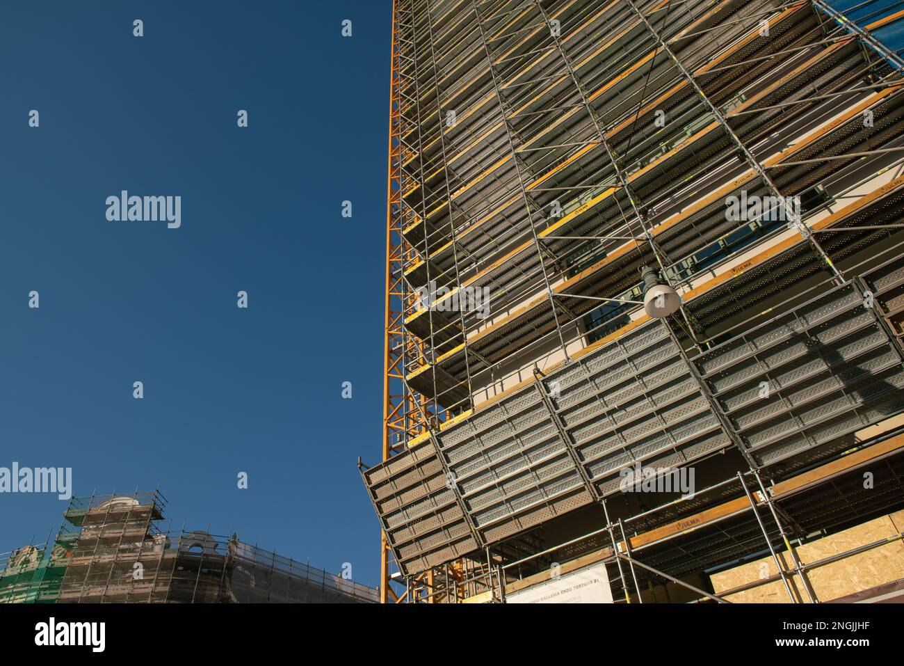 building with scaffolding and cranes, the facade of the house is clad ...