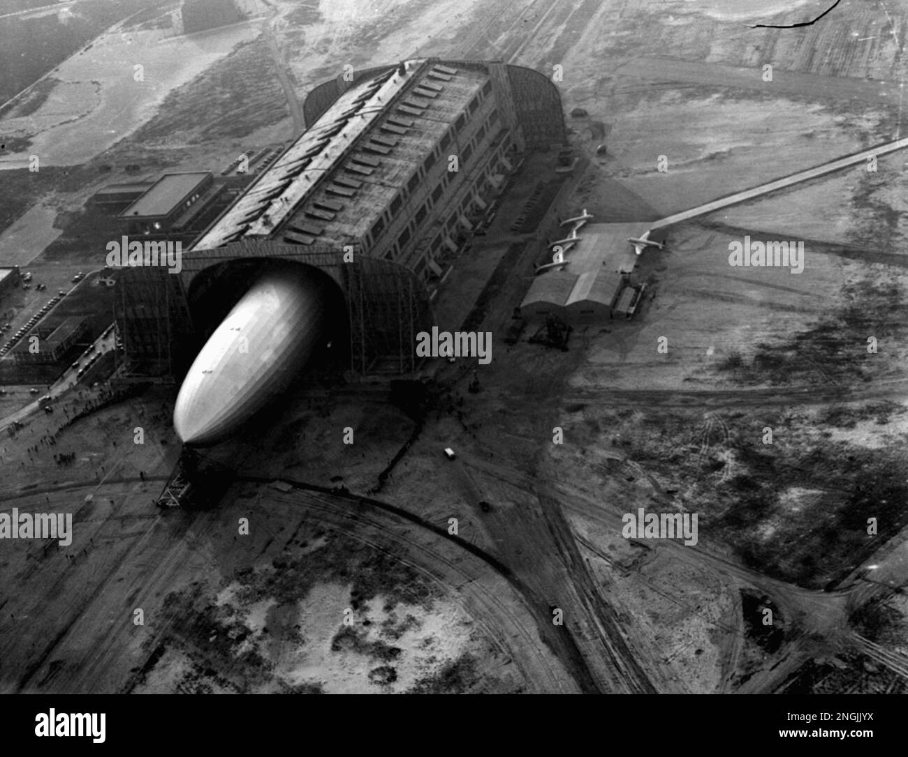 The German zeppelin Hindenburg, its nose hooked to a mooring mast, is ...