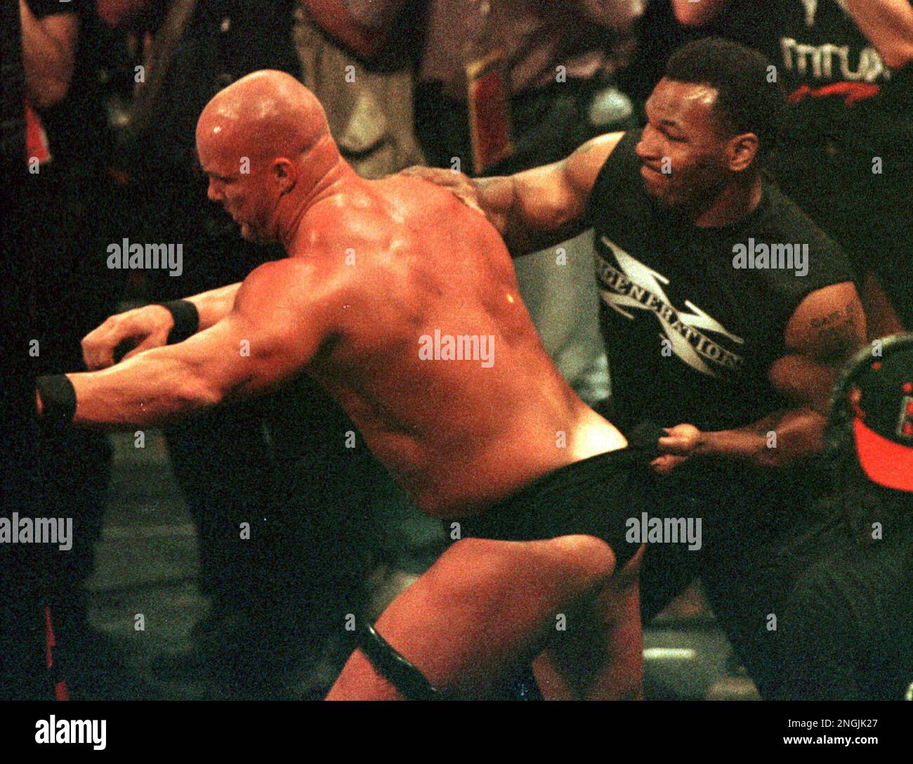 Boxer Mike Tyson, right, throws wrestler Stone Cold Steve Austin back ...