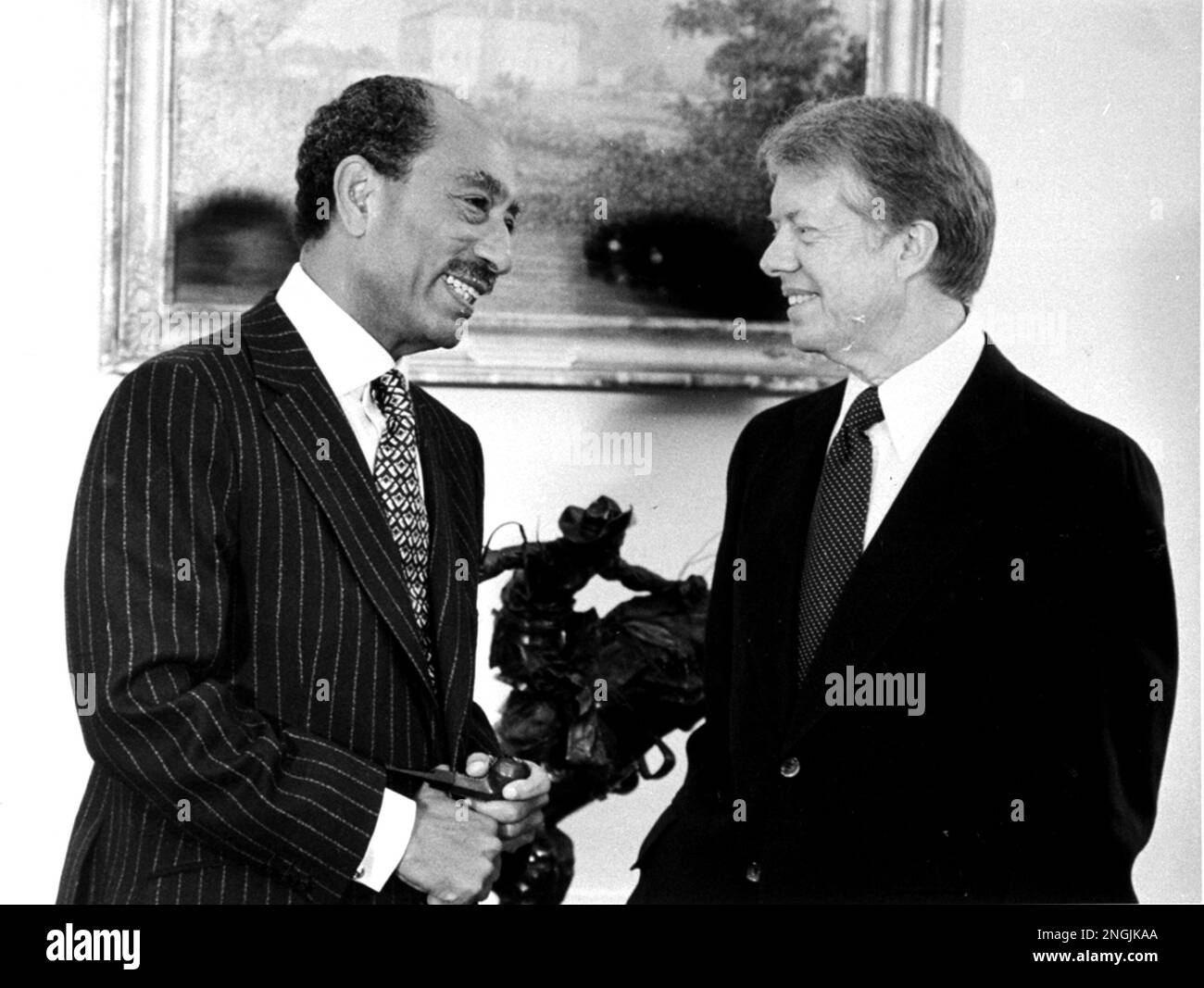 Holding his ever-present pipe, Egyptian President Anwar Sadat chats ...