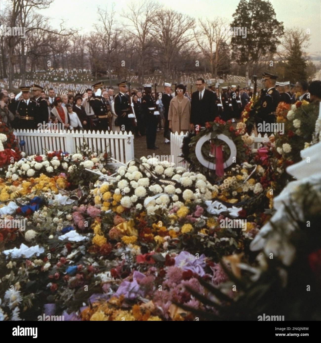 Visitors are shown at the flower-bedecked grave of President John ...