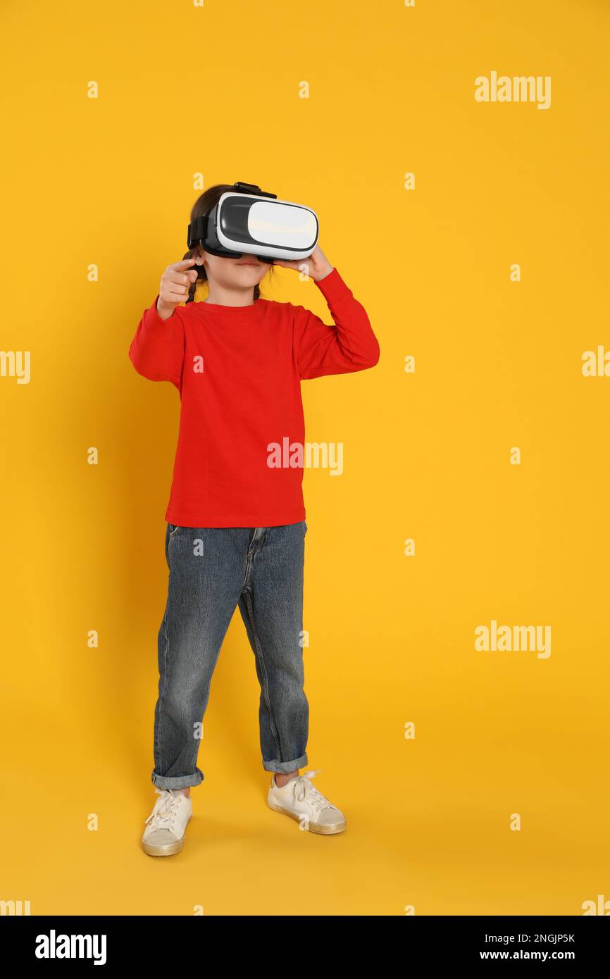 Little girl using virtual reality headset on yellow background Stock ...