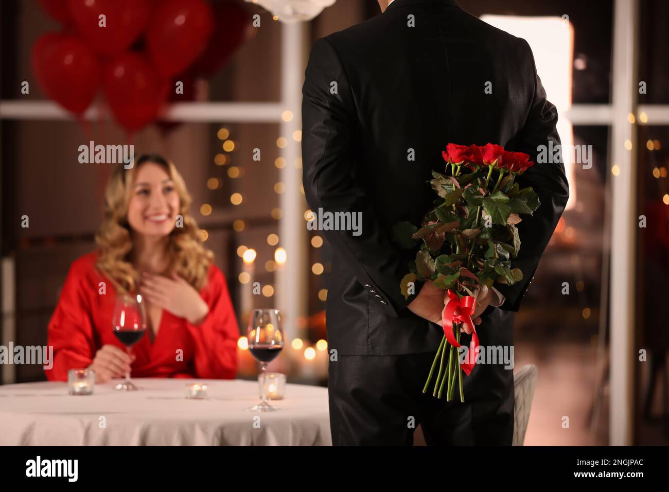 Man hiding roses for his beloved woman in restaurant at Valentine's day ...