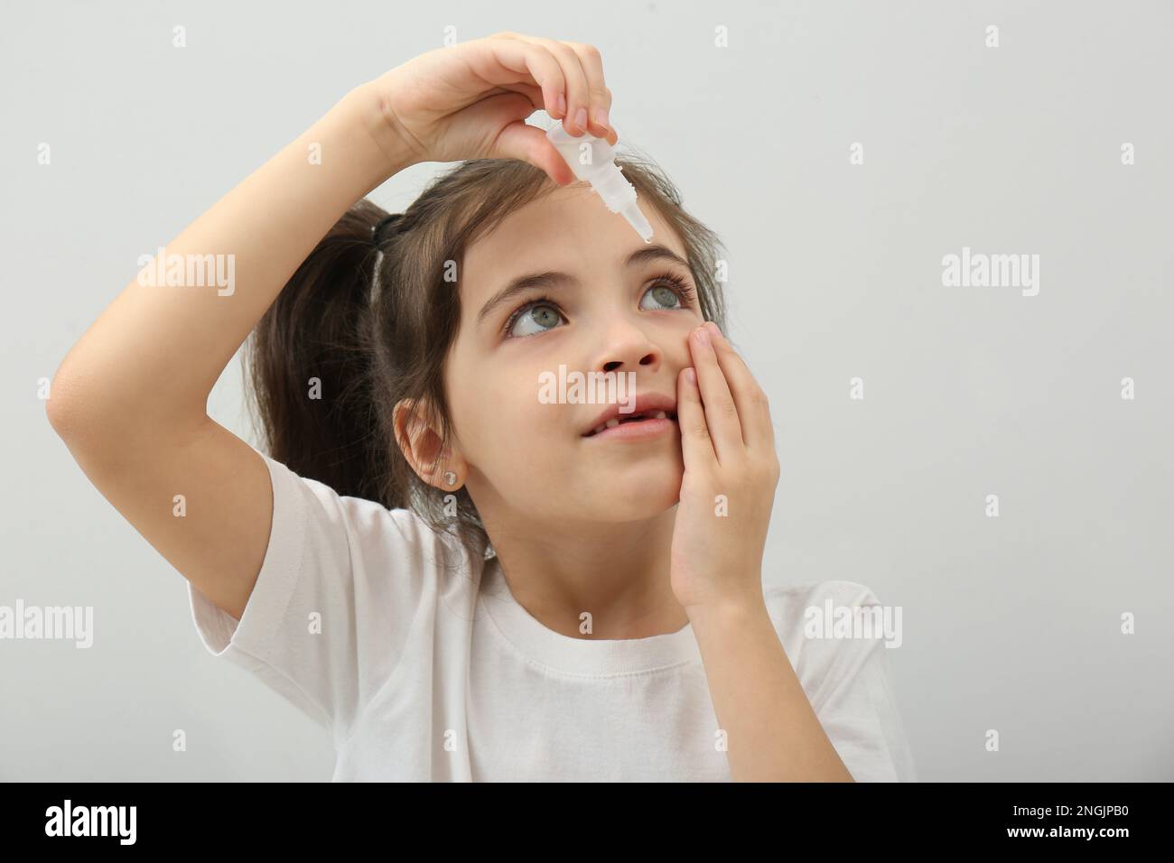 Adorable little girl using eye drops on white background Stock Photo ...