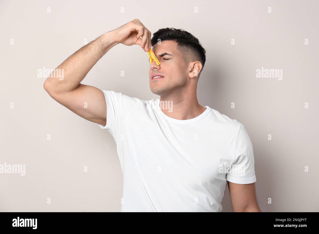 Man with clothespin on beige background. Runny nose concept Stock Photo ...
