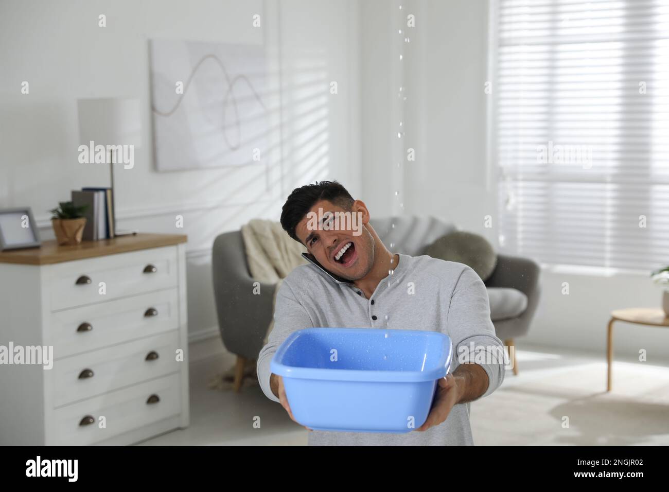 Emotional man calling roof repair service while collecting leaking ...