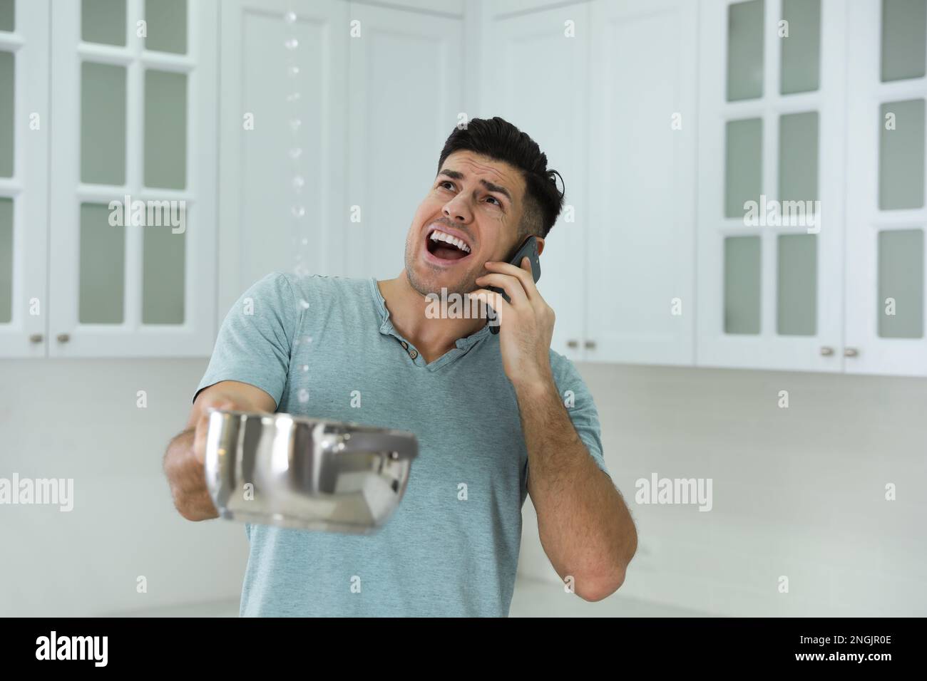 Emotional man calling roof repair service while collecting leaking ...