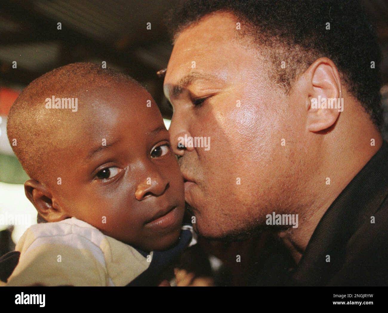Former Heavyweight boxing champion Muhammad Ali kisses an orphan child ...