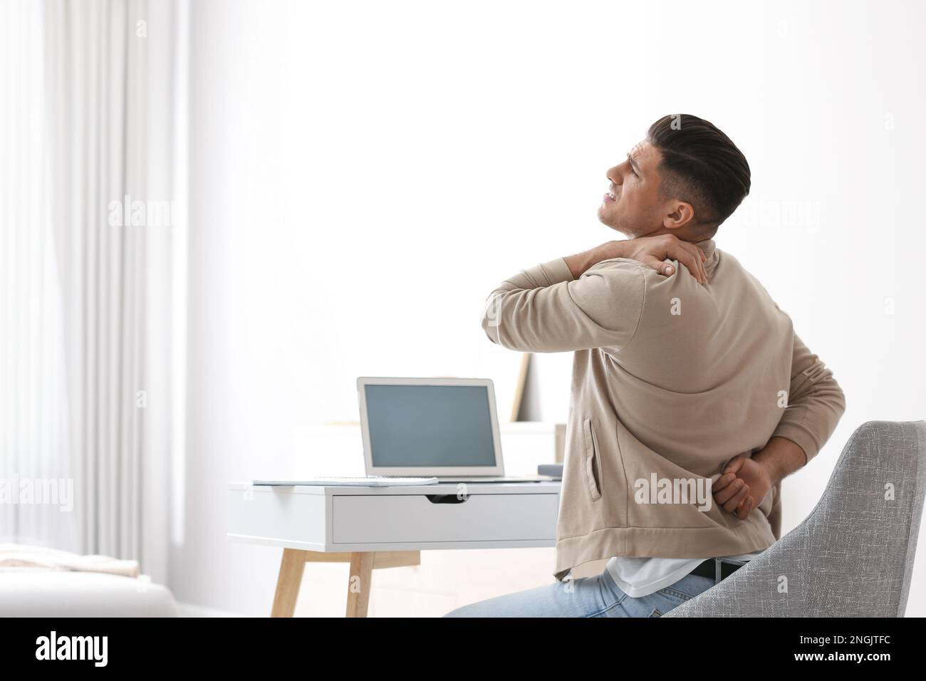 Man suffering from back pain at workplace. Bad posture problem Stock ...