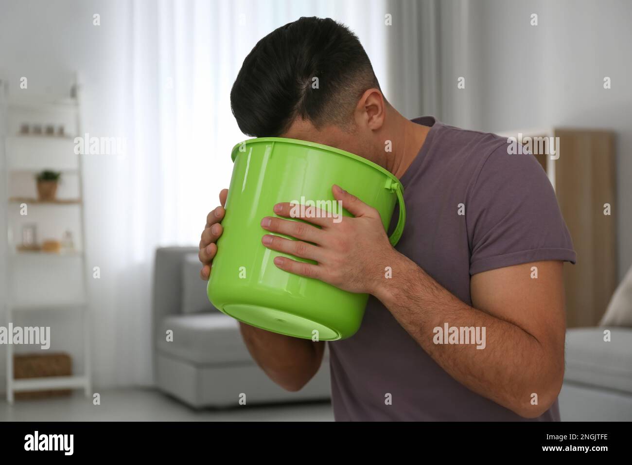 Man with bucket suffering from nausea at home. Food poisoning Stock ...