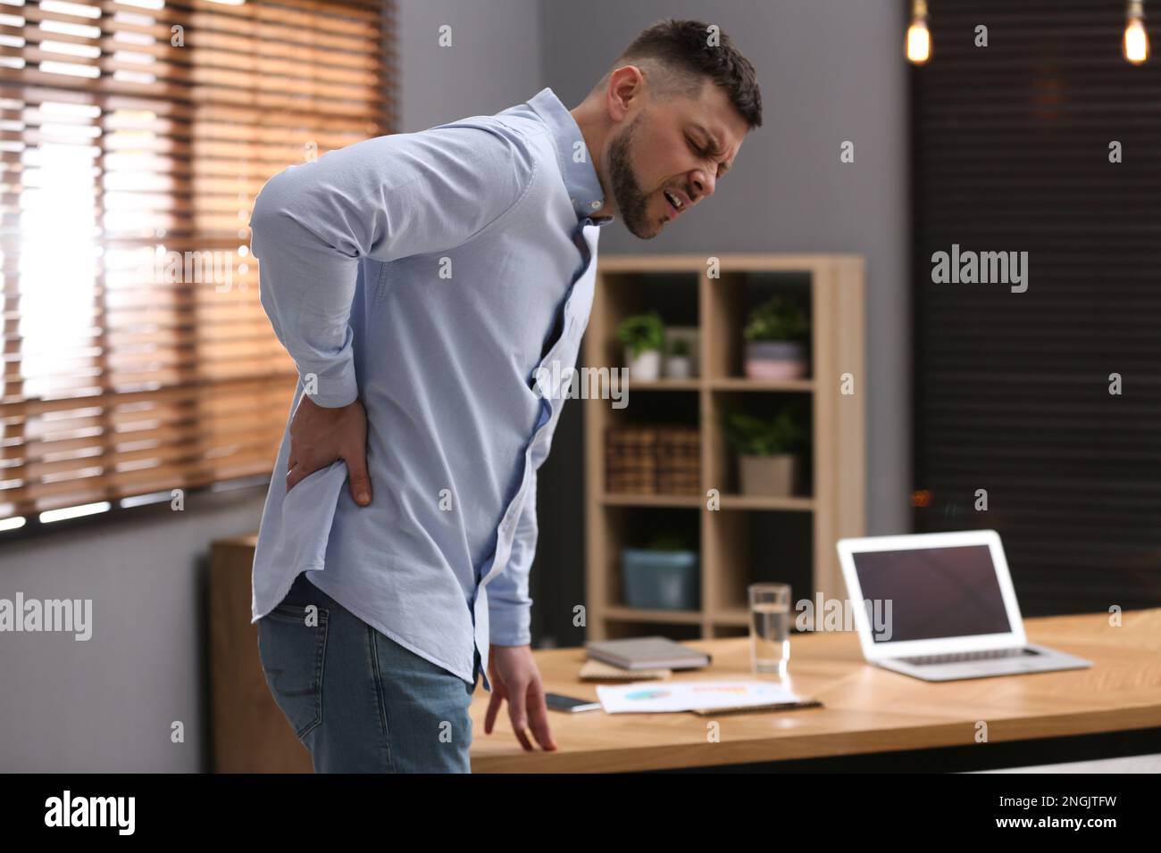 Man suffering from back pain in office. Symptom of poor posture Stock ...