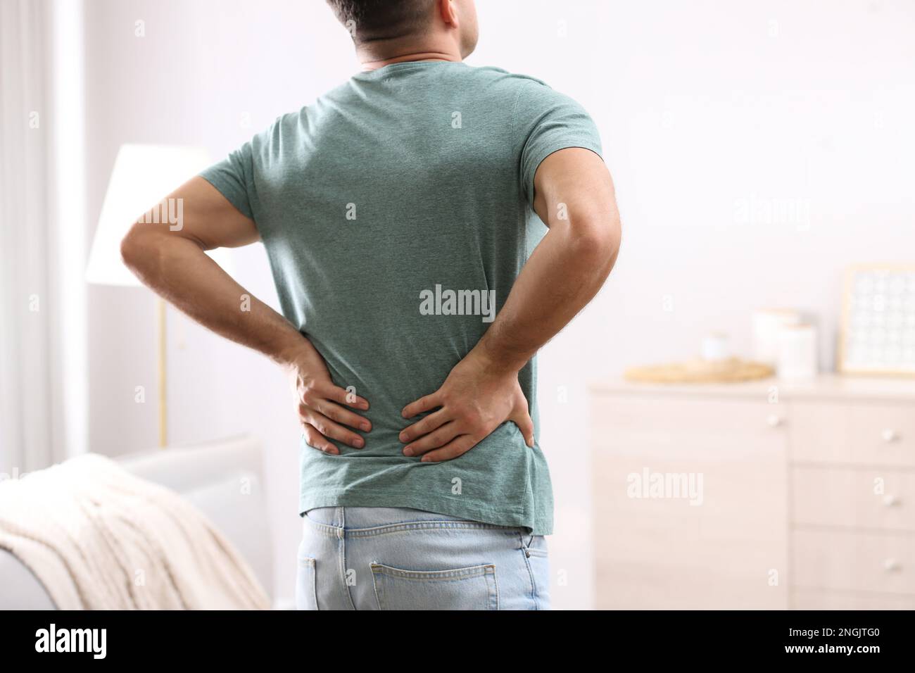 Man suffering from back pain at home. Bad posture problem Stock Photo ...