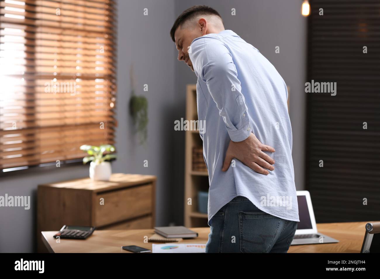 Man suffering from back pain in office. Symptom of poor posture Stock ...