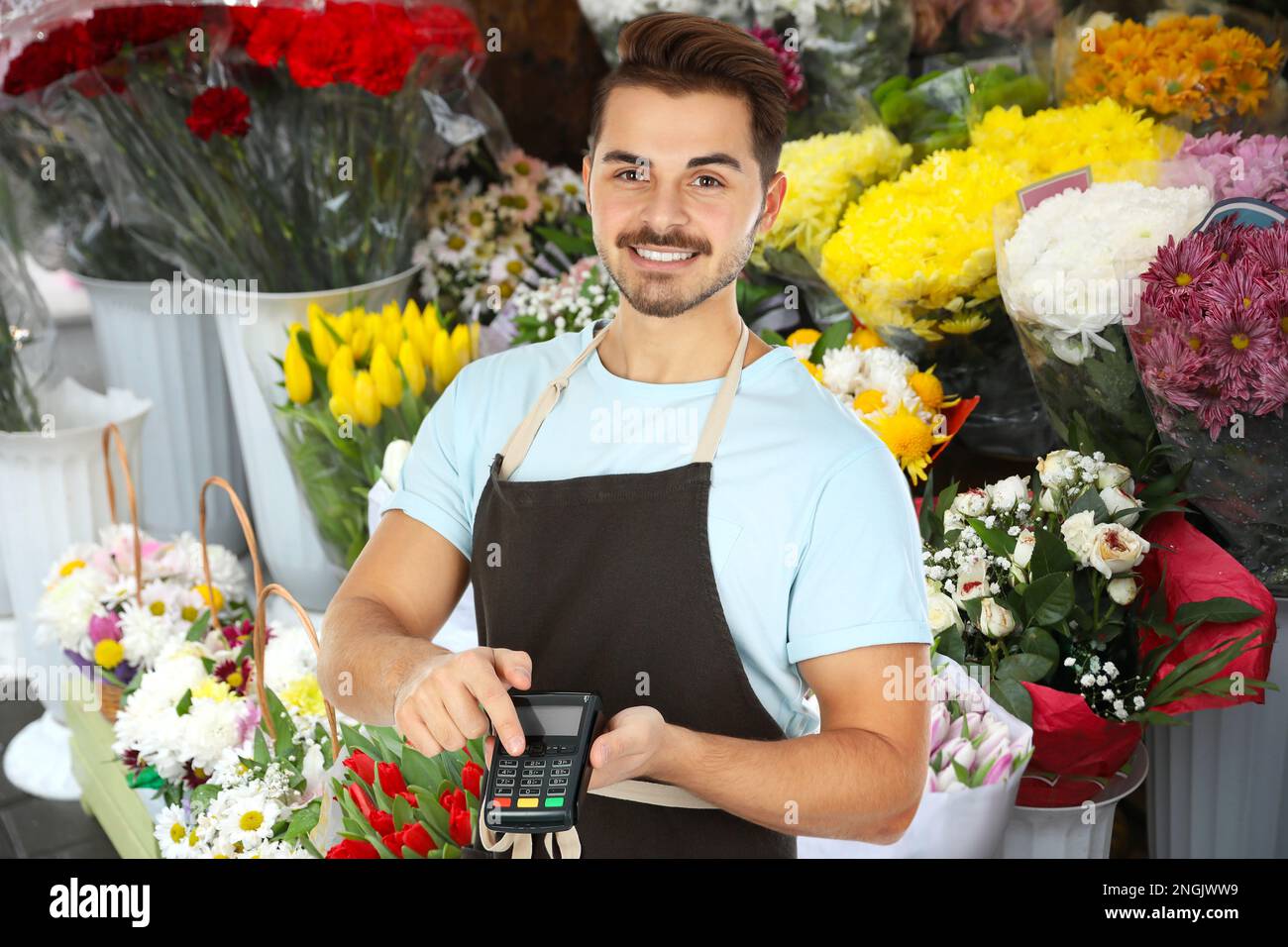 Man with terminal for contactless payment in flower shop Stock Photo ...