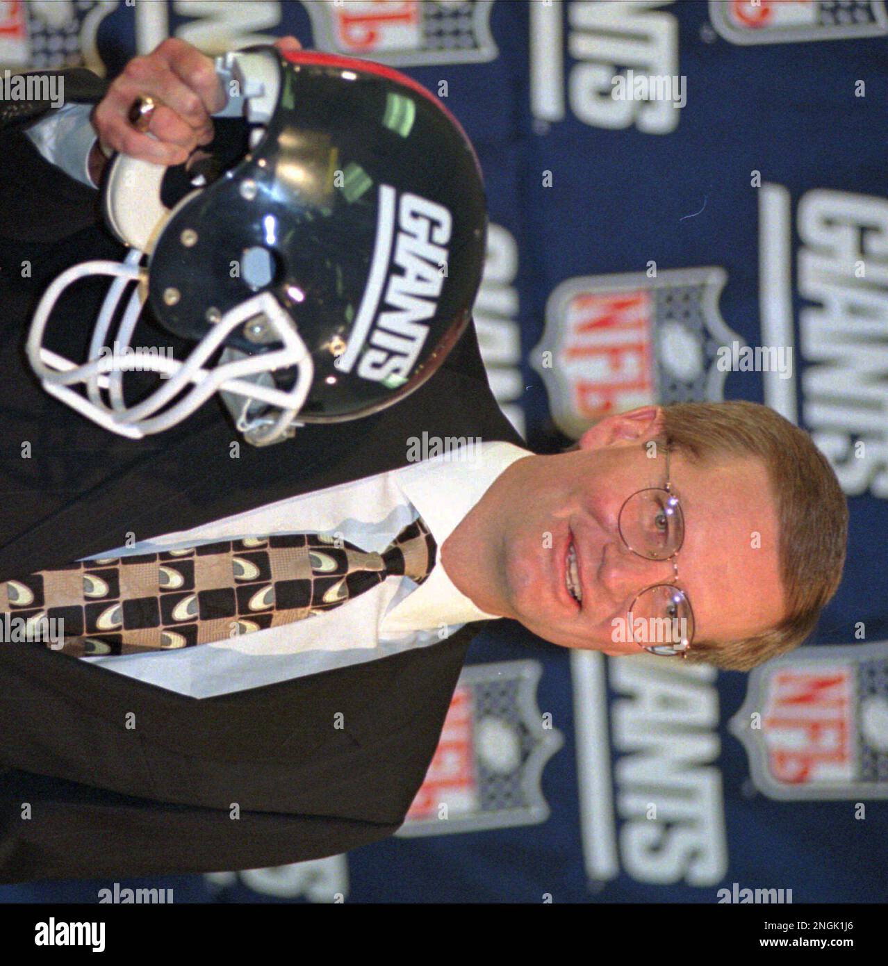 Jim Fassel holds a Giants helmet after being introduced to the media as ...