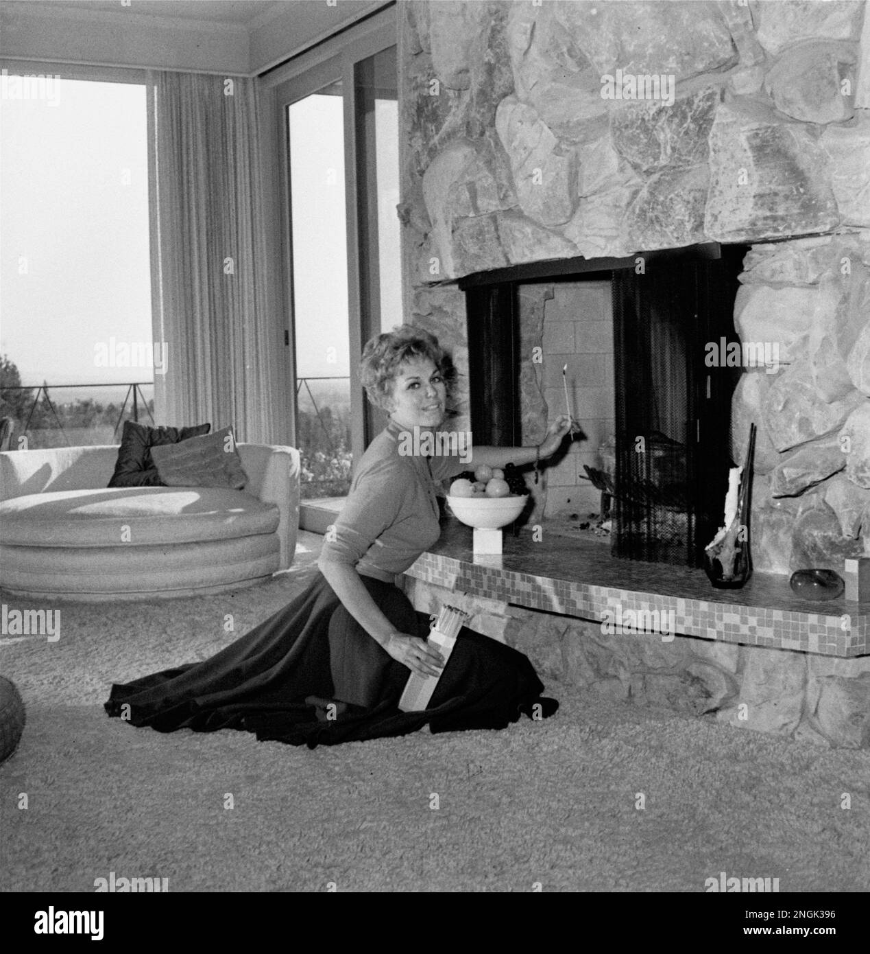Screen star Kim Novak lights the huge rock fireplace in the living room ...