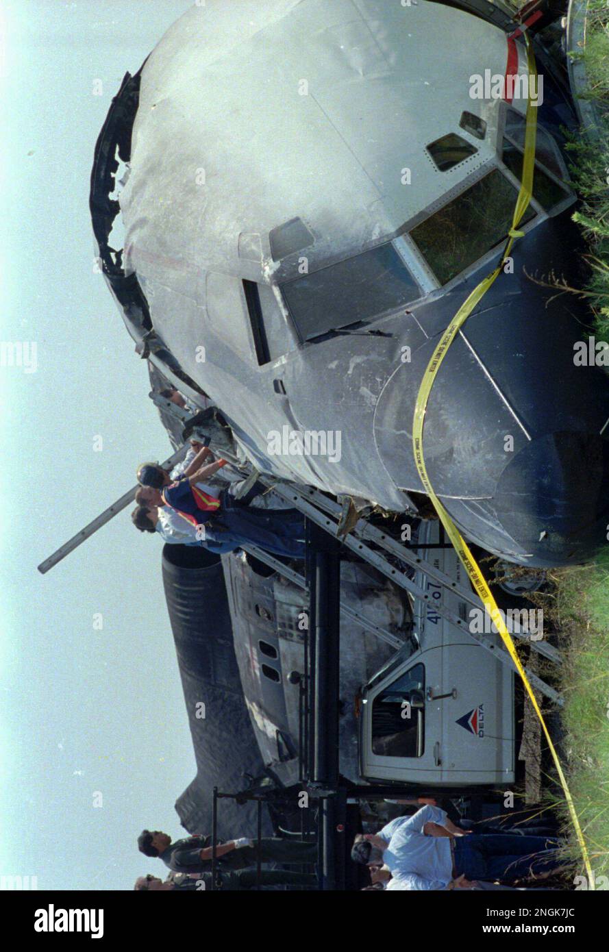 Workers remove a body from the front section of the remains of Delta ...
