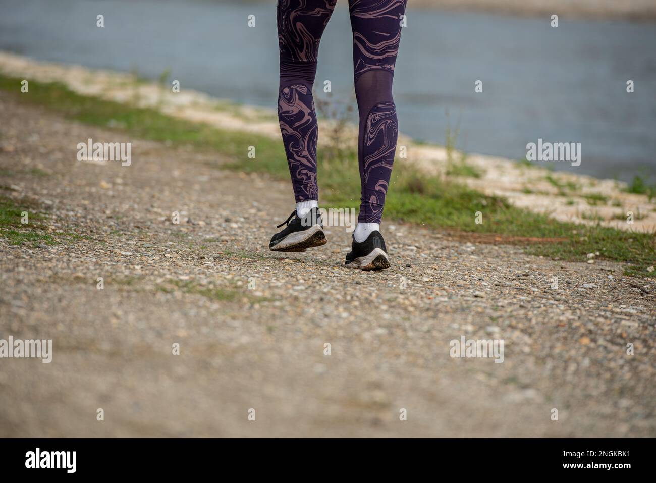Strong and fir girl is slow walking alone by the river, close up at the ...