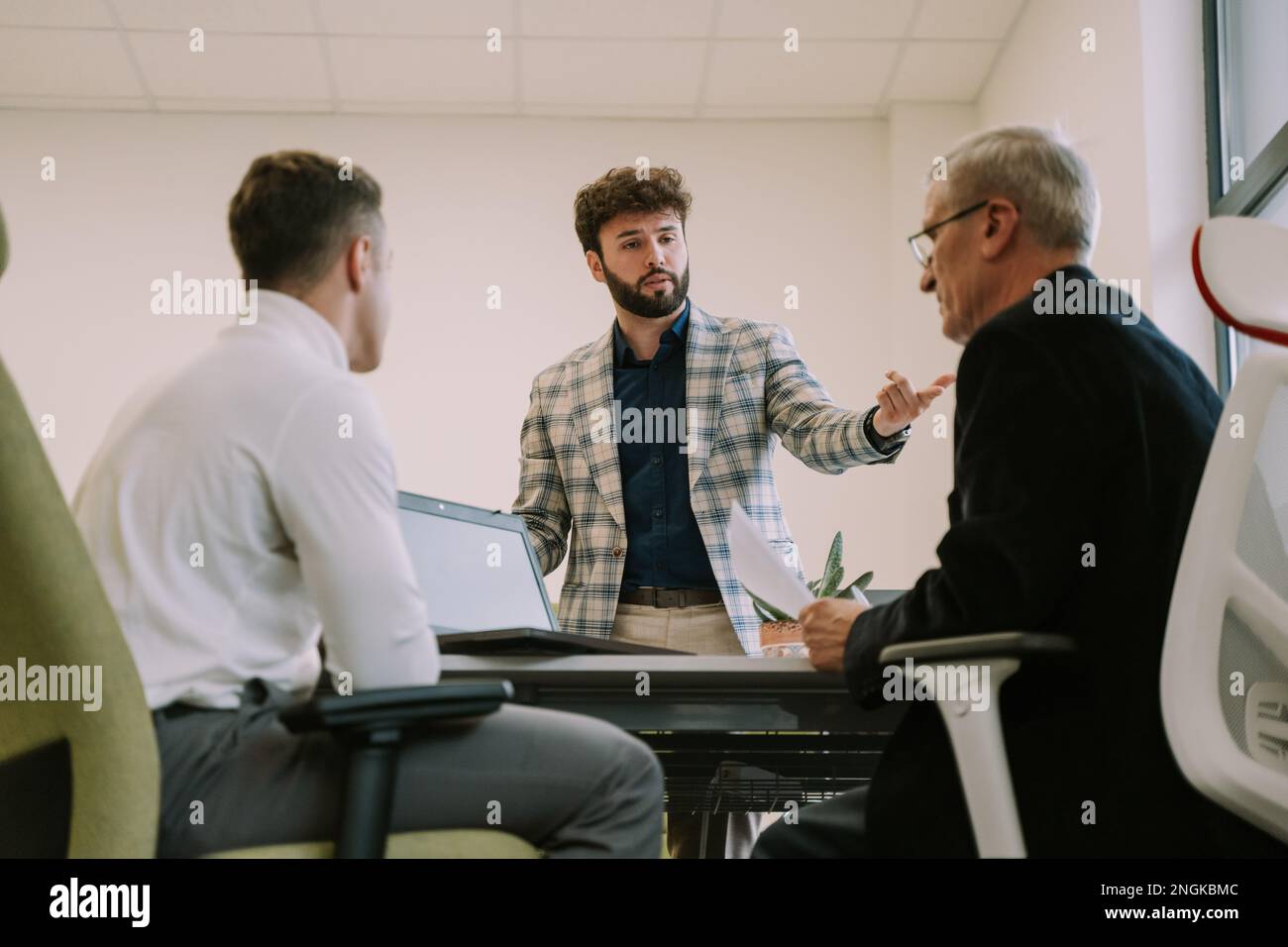 Disappointed and angry boss overlooking and correcting his employees at ...