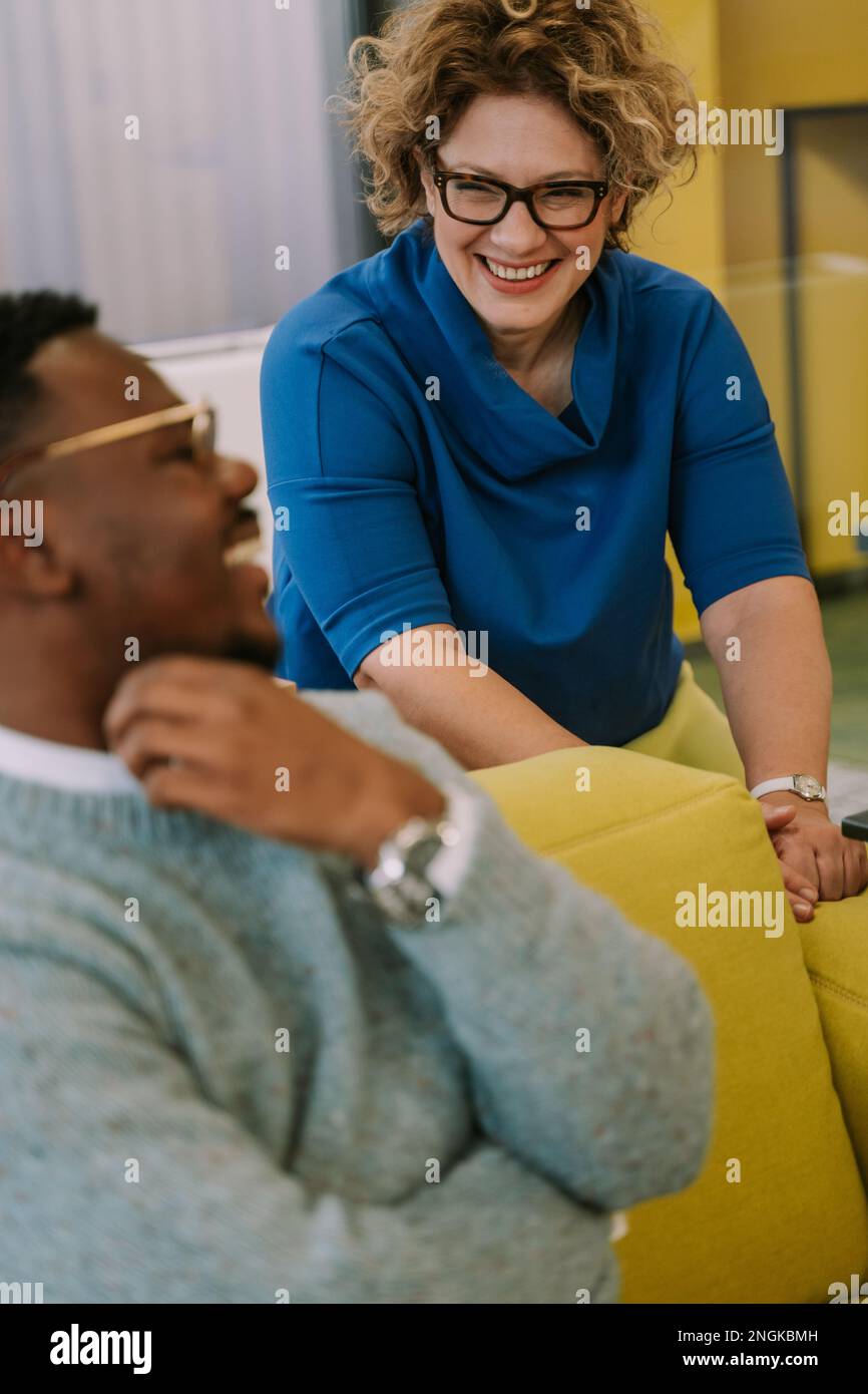 Two multiracial coworkers are having a very fun conversation. The man ...