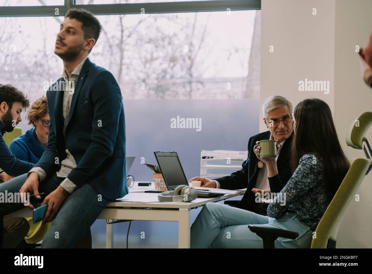 Formal and well dressed senior man tutoring the newly promoted girl at ...