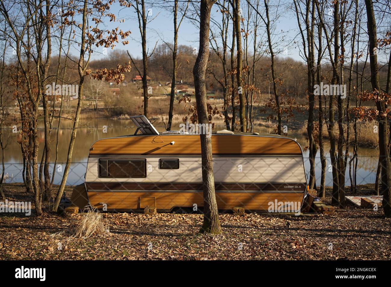 Yellow camper in the forest by the lake Stock Photo - Alamy