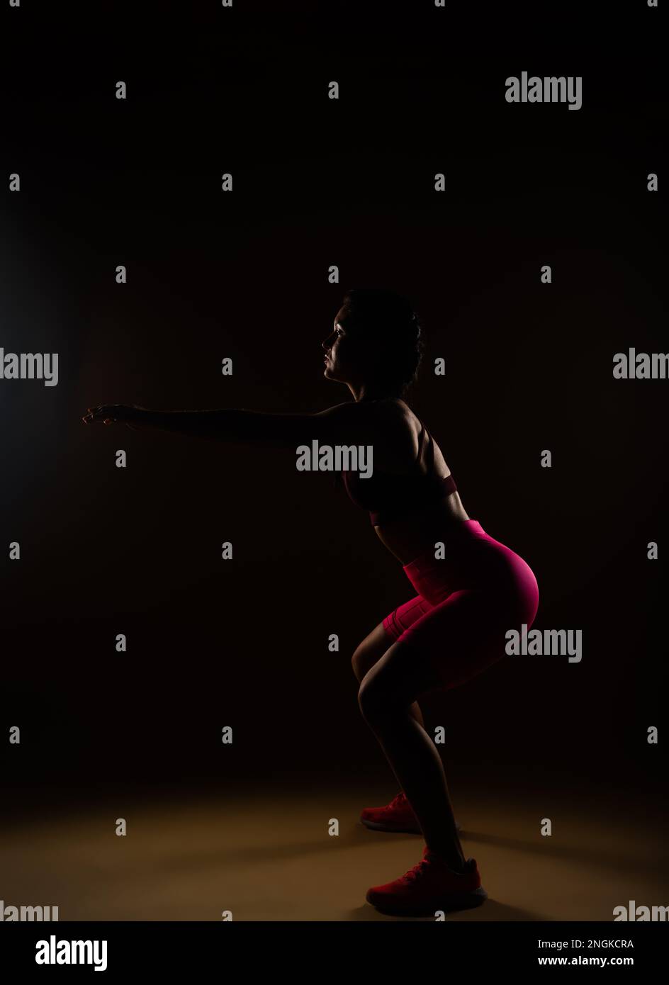 A side view photo of sporty woman doing squats with straighten arms ...