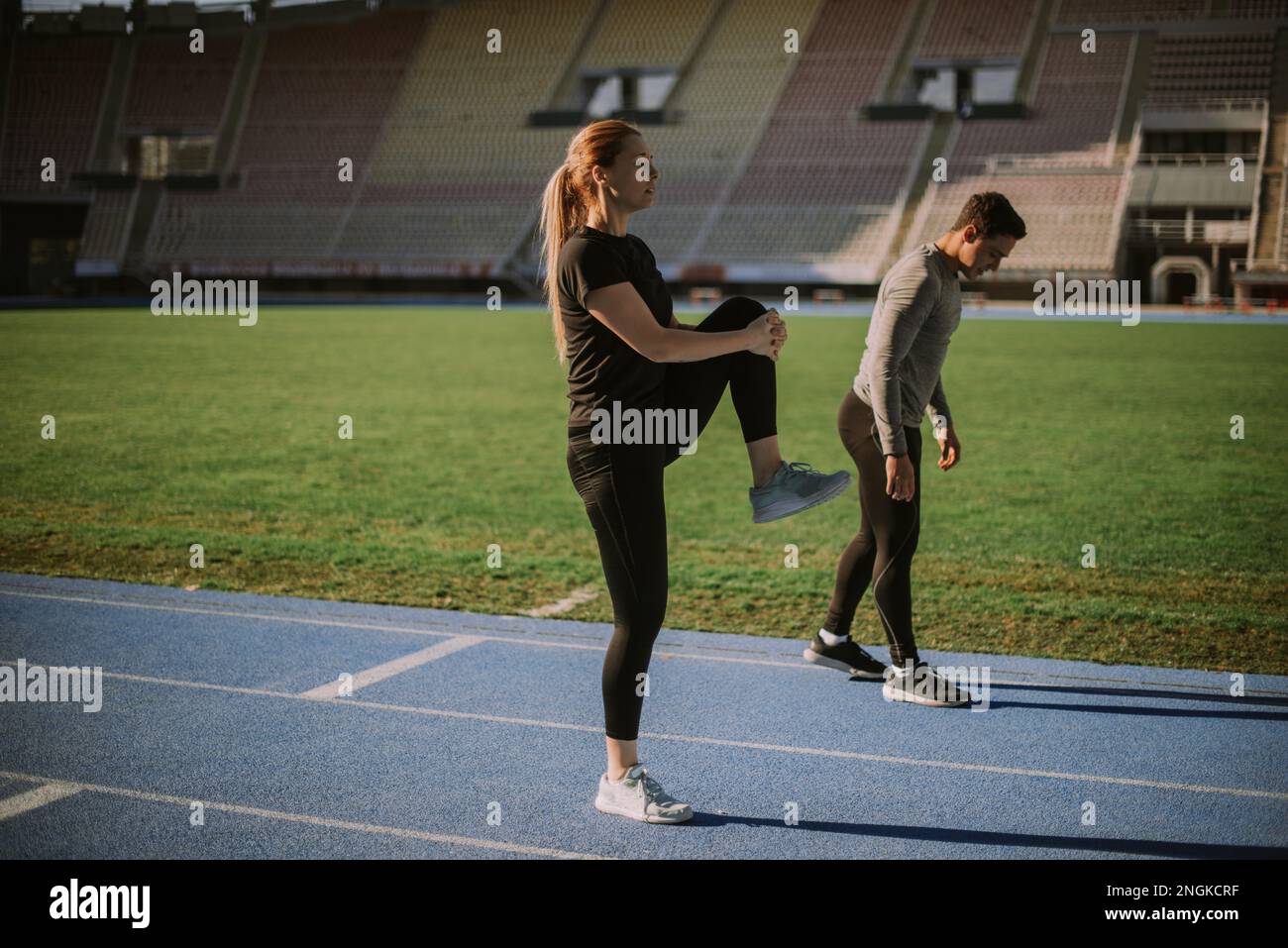 Alluring sports couple is warming up together. The girl is stretching ...