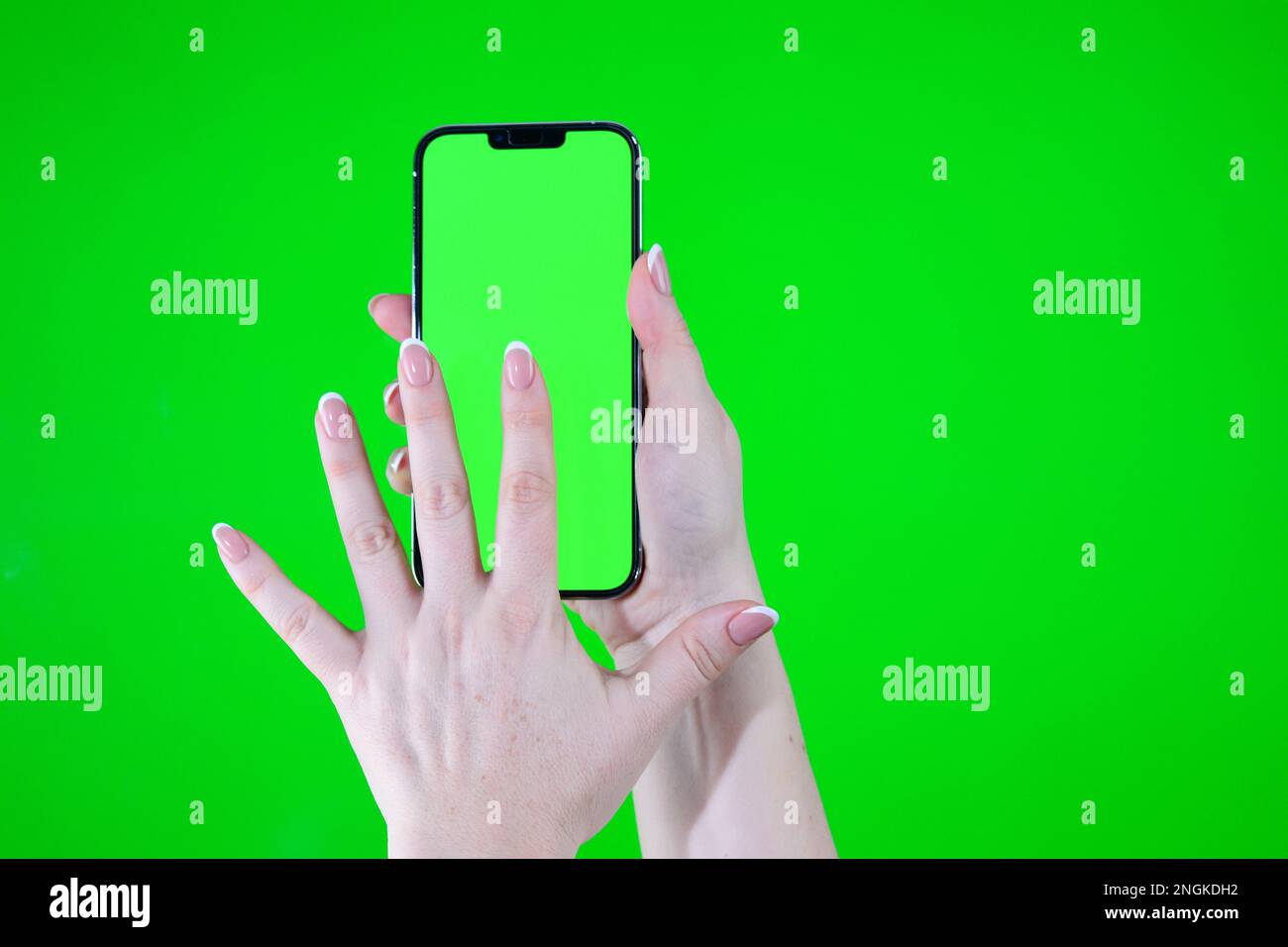 Beautiful girl holding a smartphone in the hands of a green screen ...