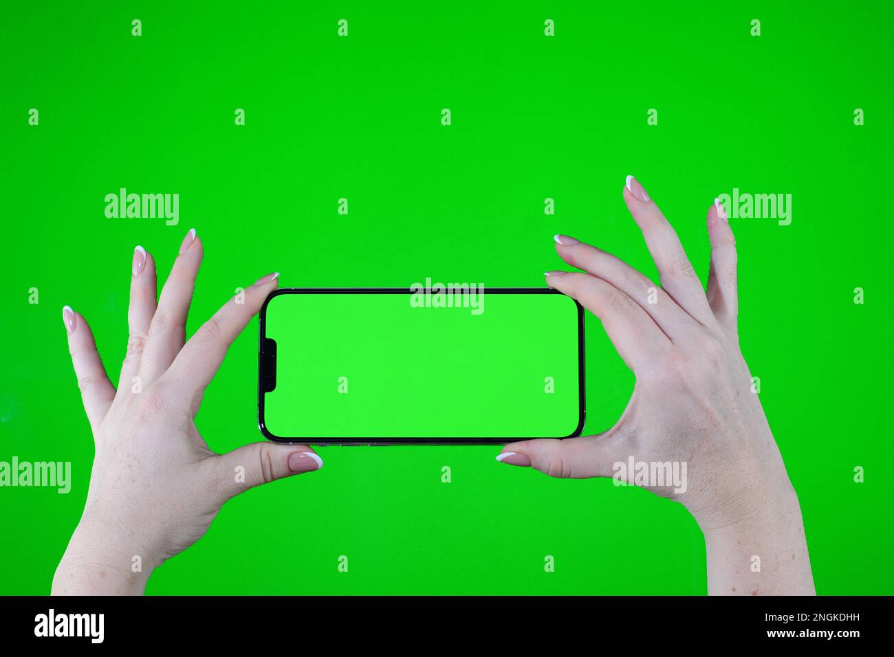 Beautiful girl holding a smartphone in the hands of a green screen ...