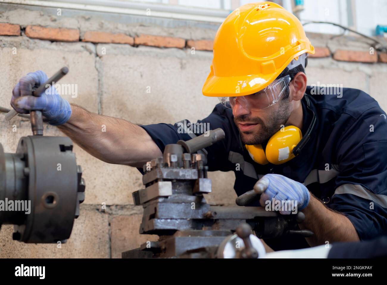 Young caucasian engineer man operating lathe machine for preparing ...