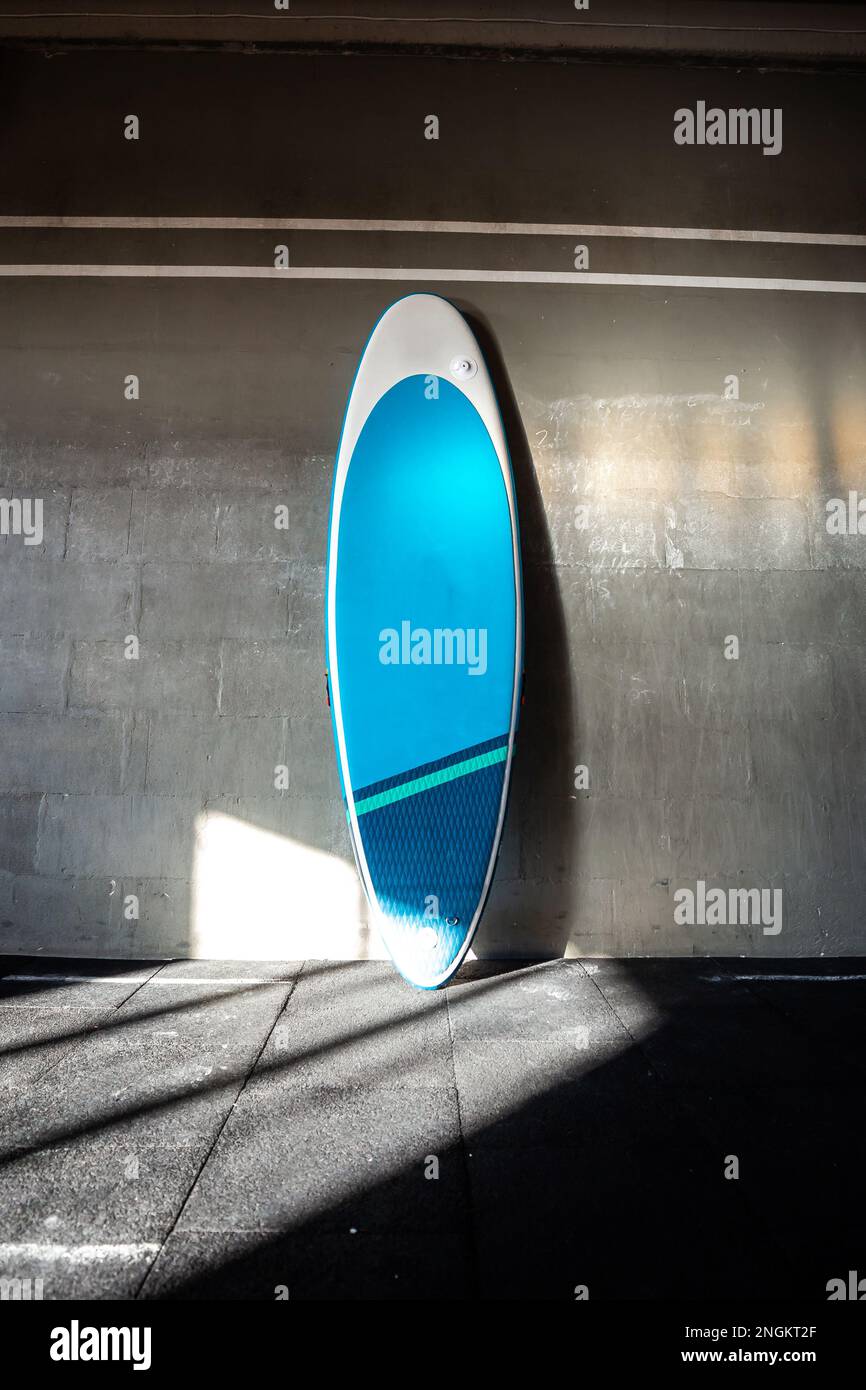 Blue inflatable stand-up paddle board SUP by the wall. Surfing and sup ...