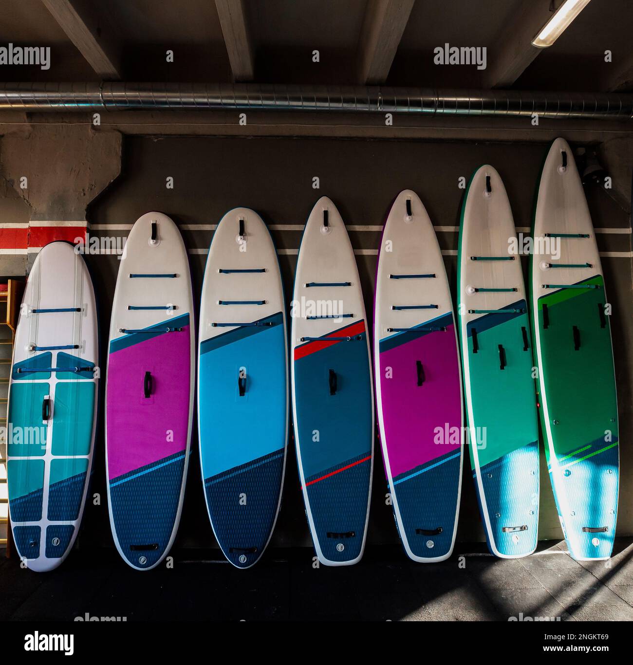 Colorful inflatable stand-up paddle boards SUP by the wall. Surfing and ...