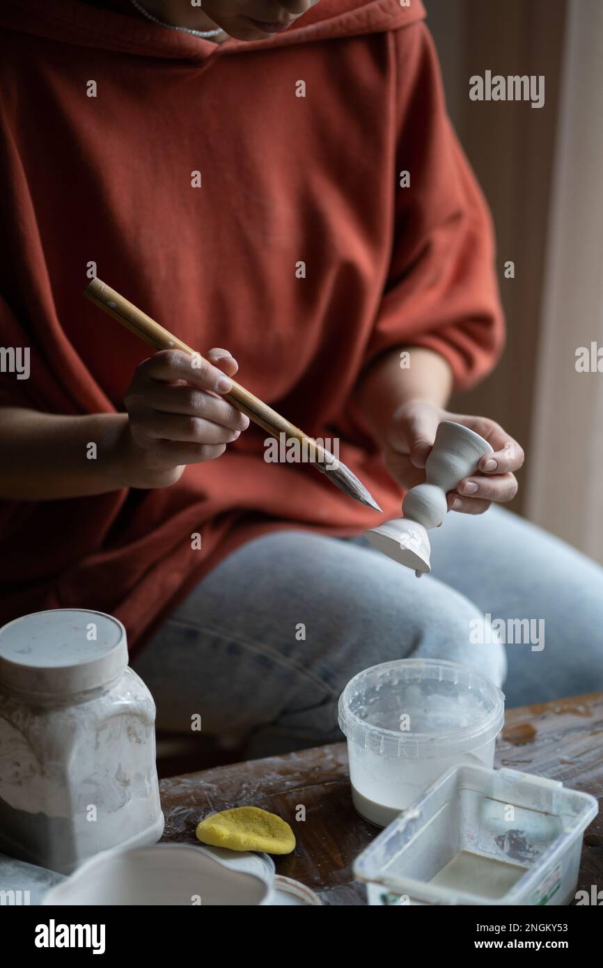 Craft woman holds clay product created using brush and water to smooth ...