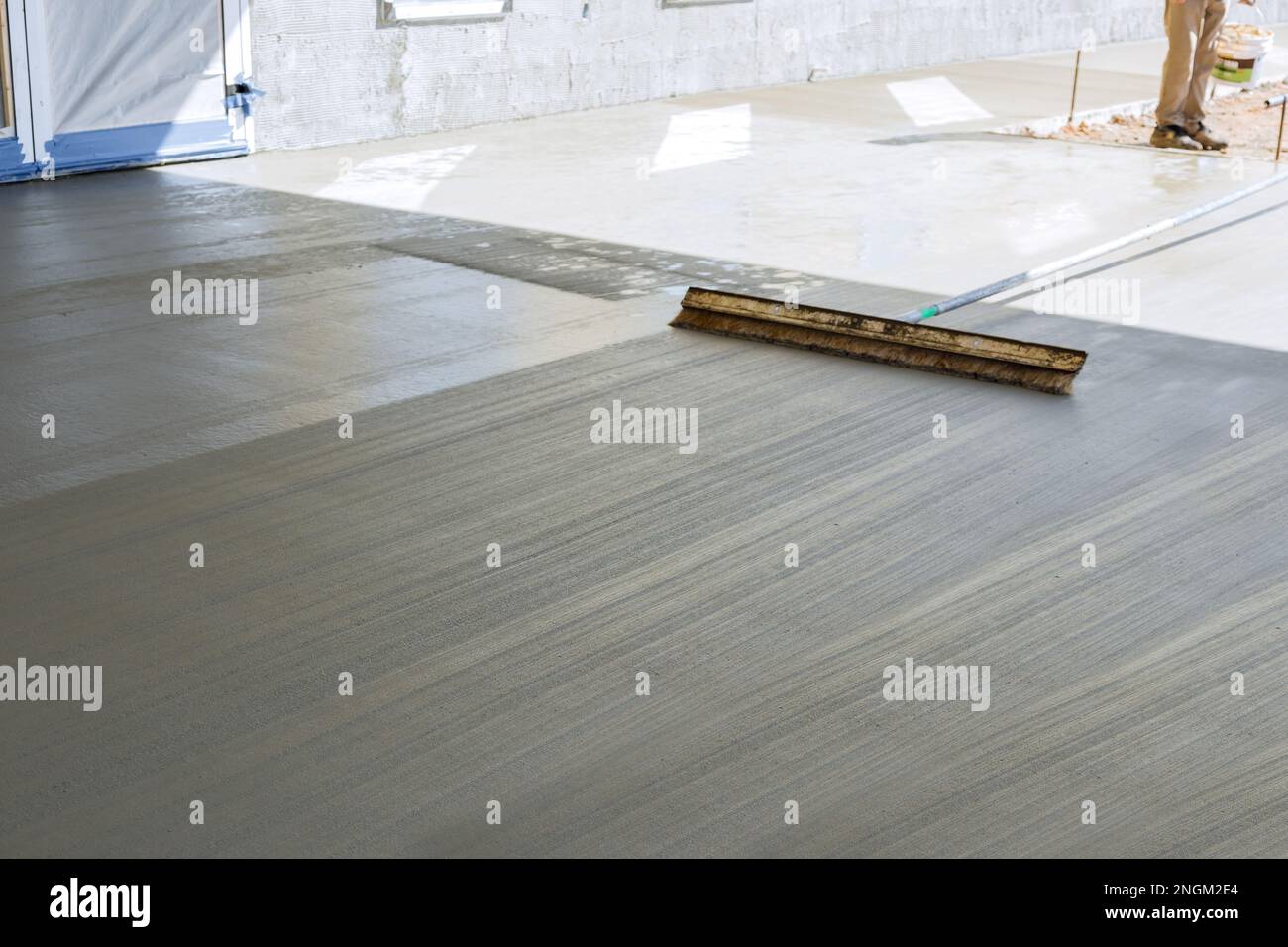 An employee of construction company uses broom to surface of fresh wet ...
