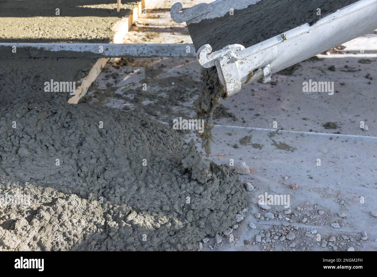 Concrete mixing truck pours concrete for surrounding pavement of newly ...