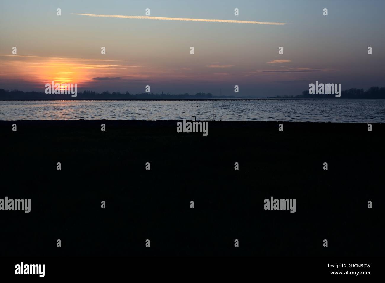 Lake at sunset with the opposite shore on the horizon Stock Photo - Alamy