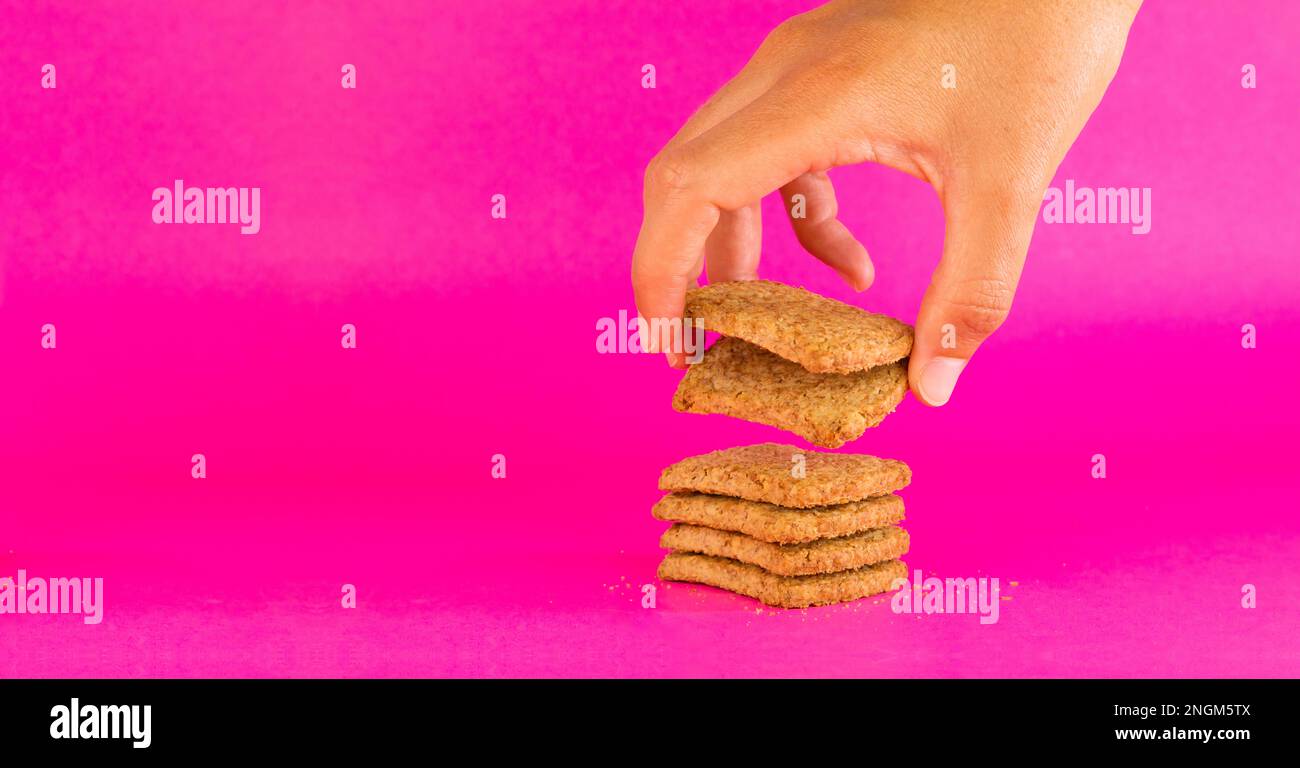 A young woman's hand, picking up a cookie from a stack of whole wheat ...