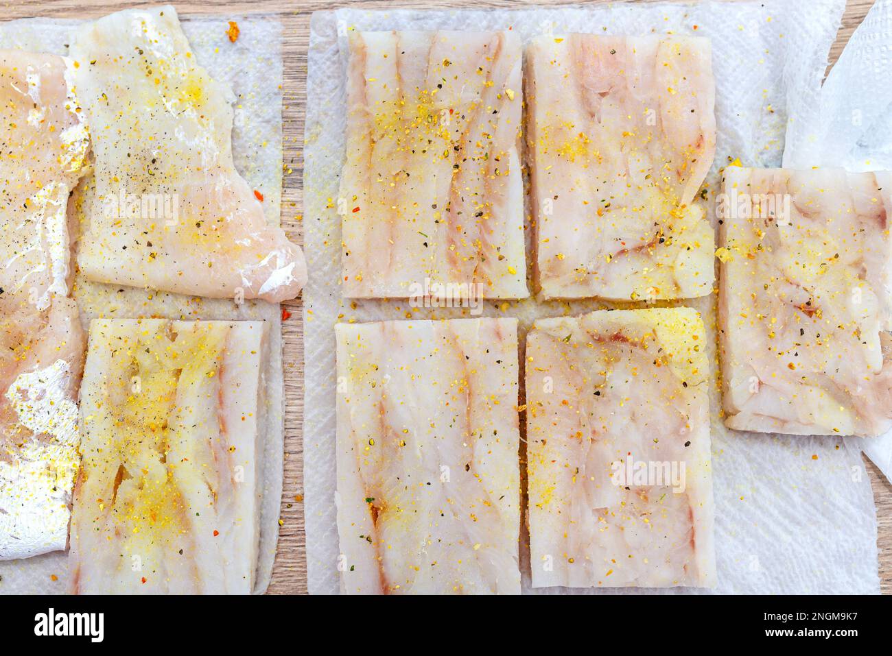 Fresh cod fillet cut into squares, sprinkled with spices lying on a ...
