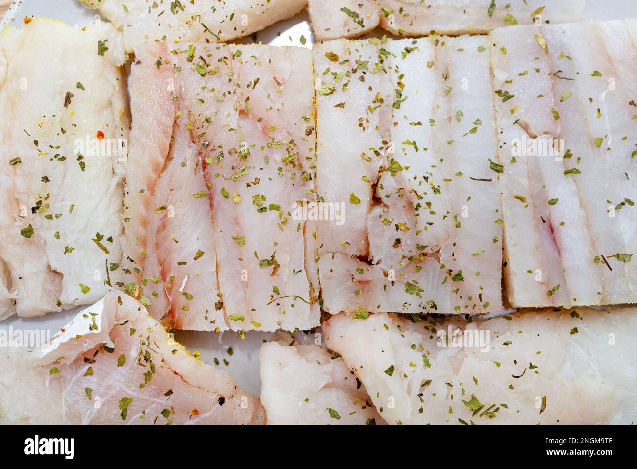 Background made of cod fish fillet cut into squares and sprinkled with ...
