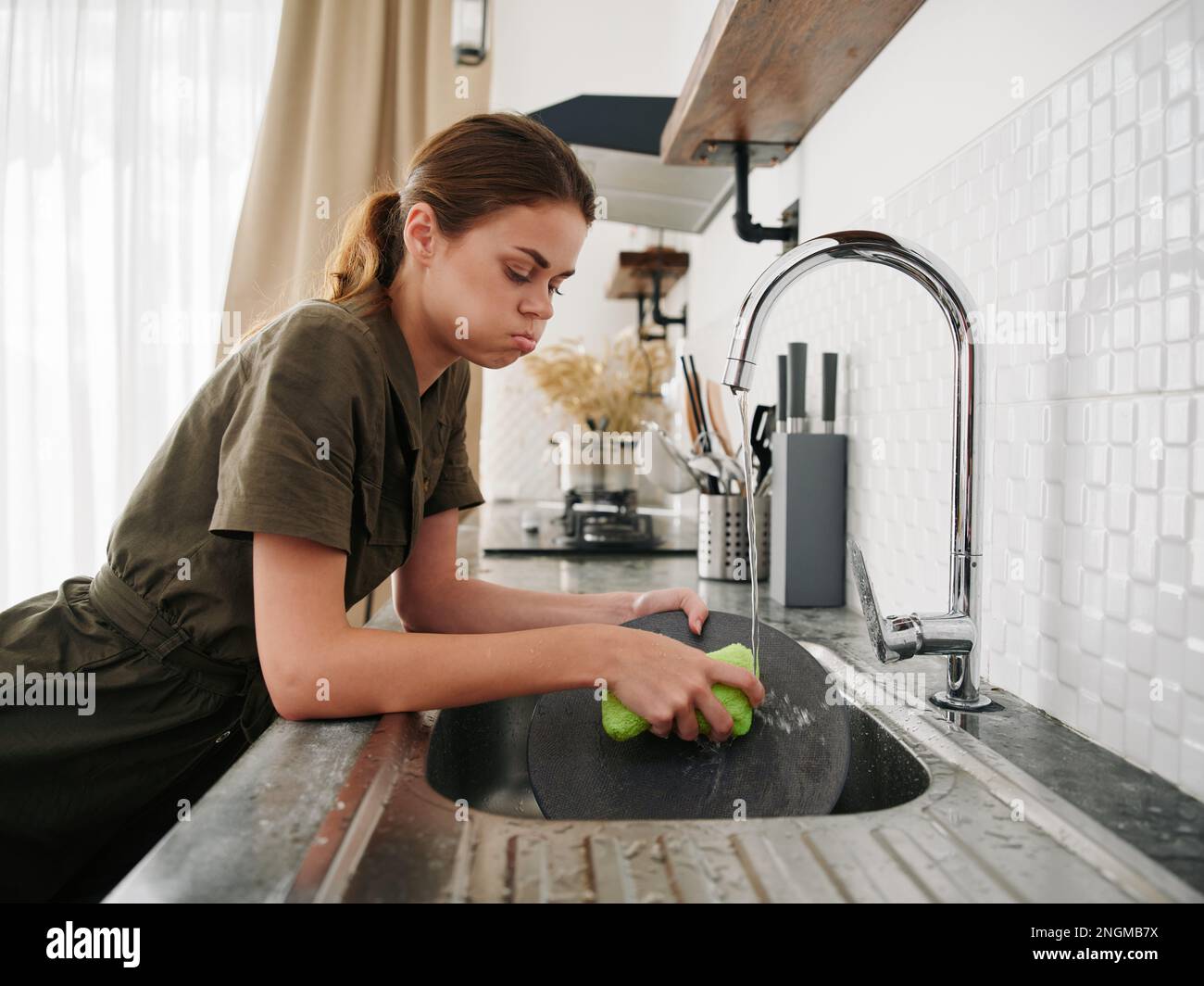 Woman tired and angry hands without gloves washes dishes with a ...