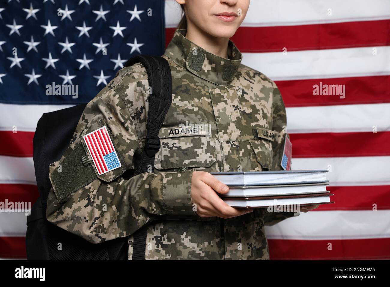 Female cadet with backpack and books against American flag, closeup ...