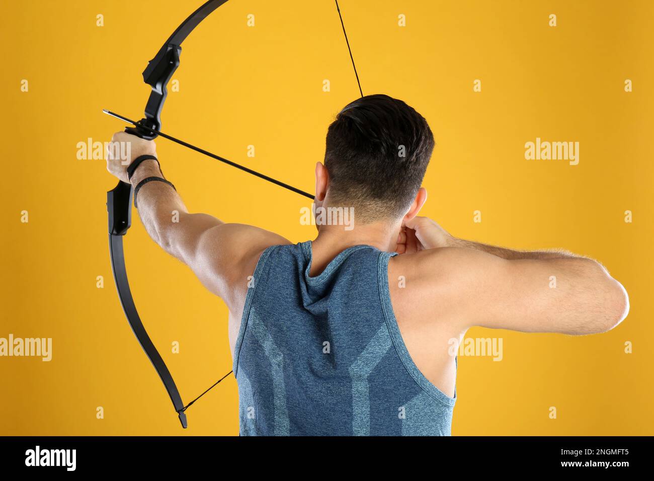 Man with bow and arrow practicing archery on yellow background, back ...