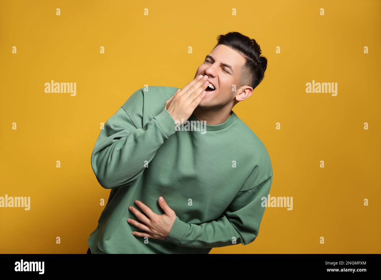 Handsome man laughing on yellow background. Funny joke Stock Photo - Alamy