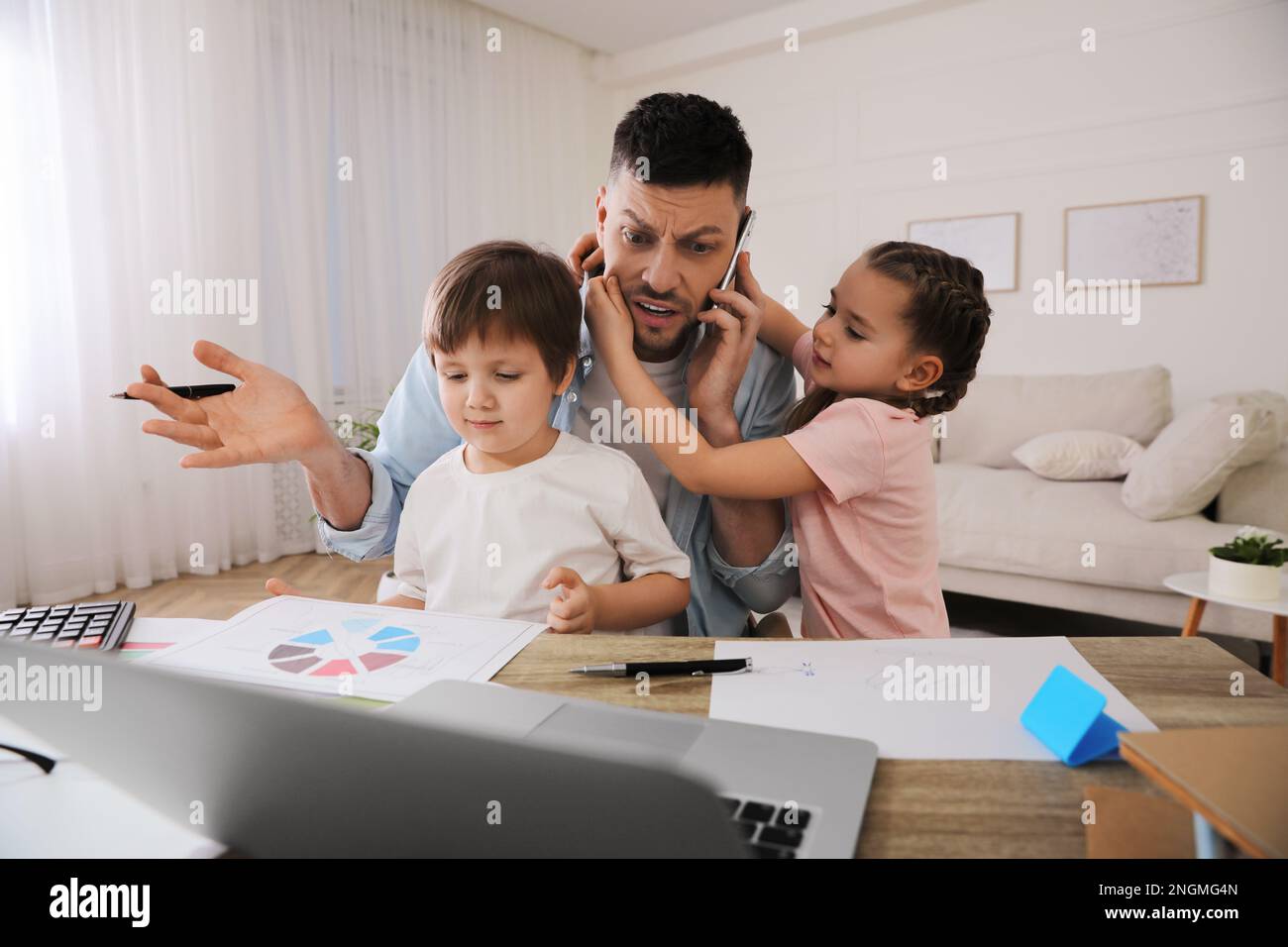 Overwhelmed man combining parenting and work at home Stock Photo - Alamy